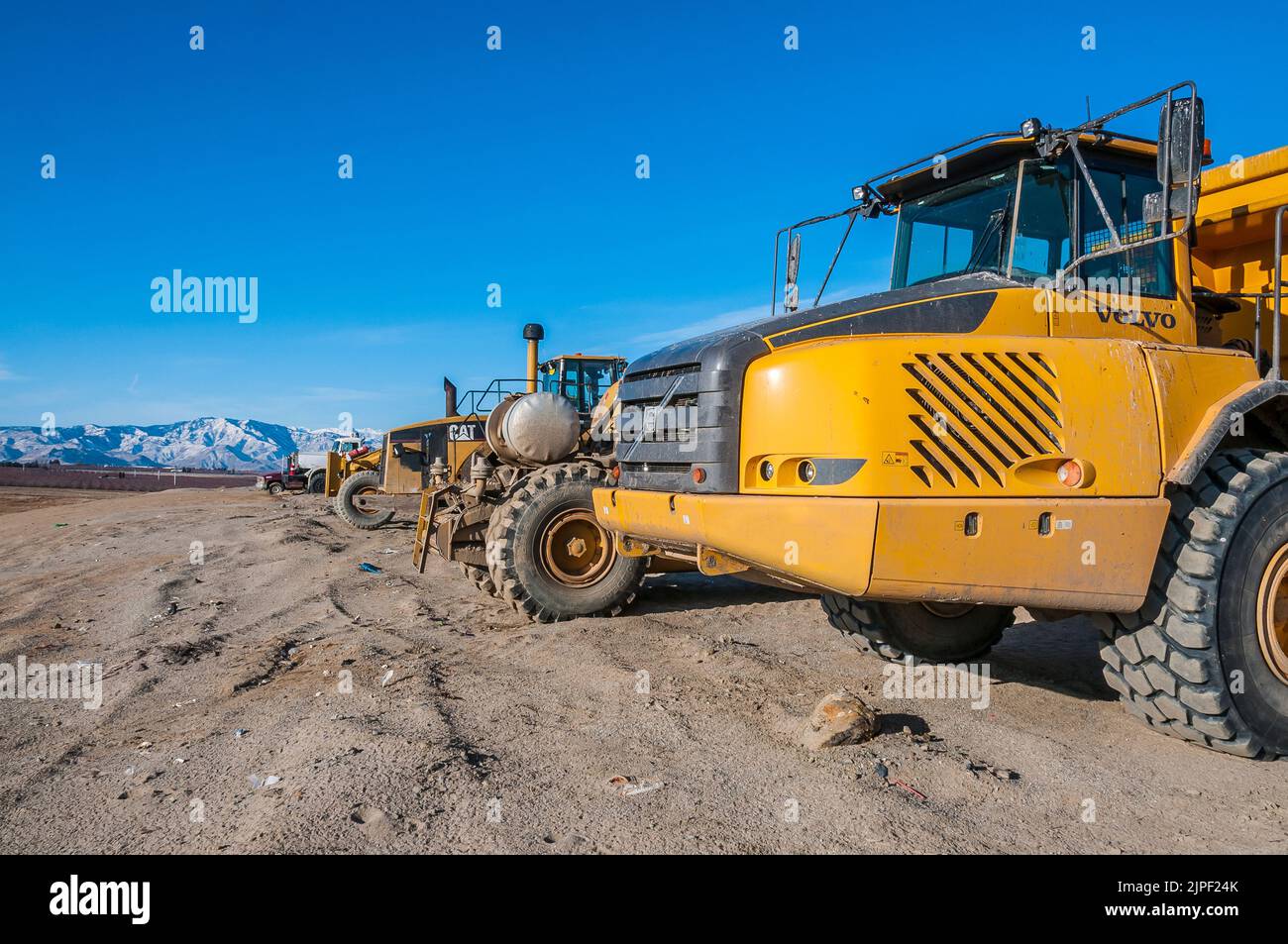 Heavy equipment vehicles lined up at an active landfill site. The ...