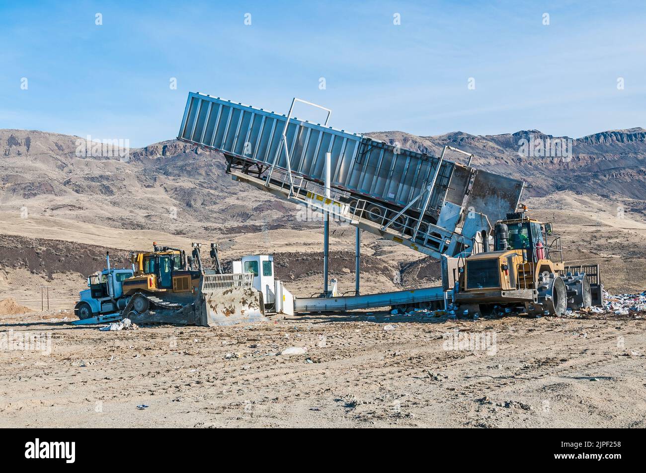 Landfill tipper lifts trailer container to dump trash into an active ...