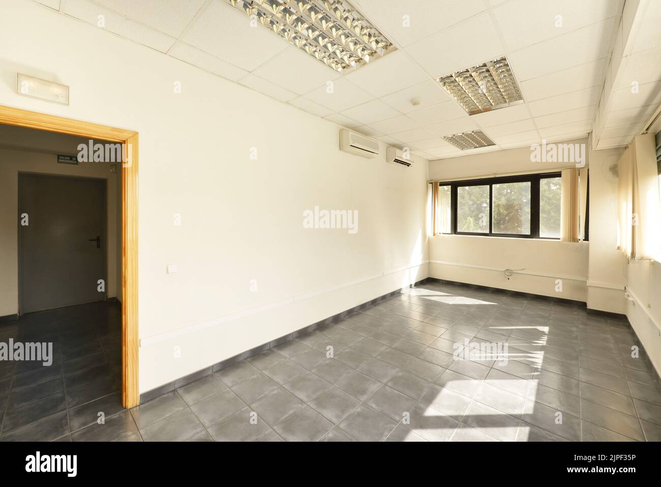 Empty offices with gray stoneware floors, windows on several walls and ...