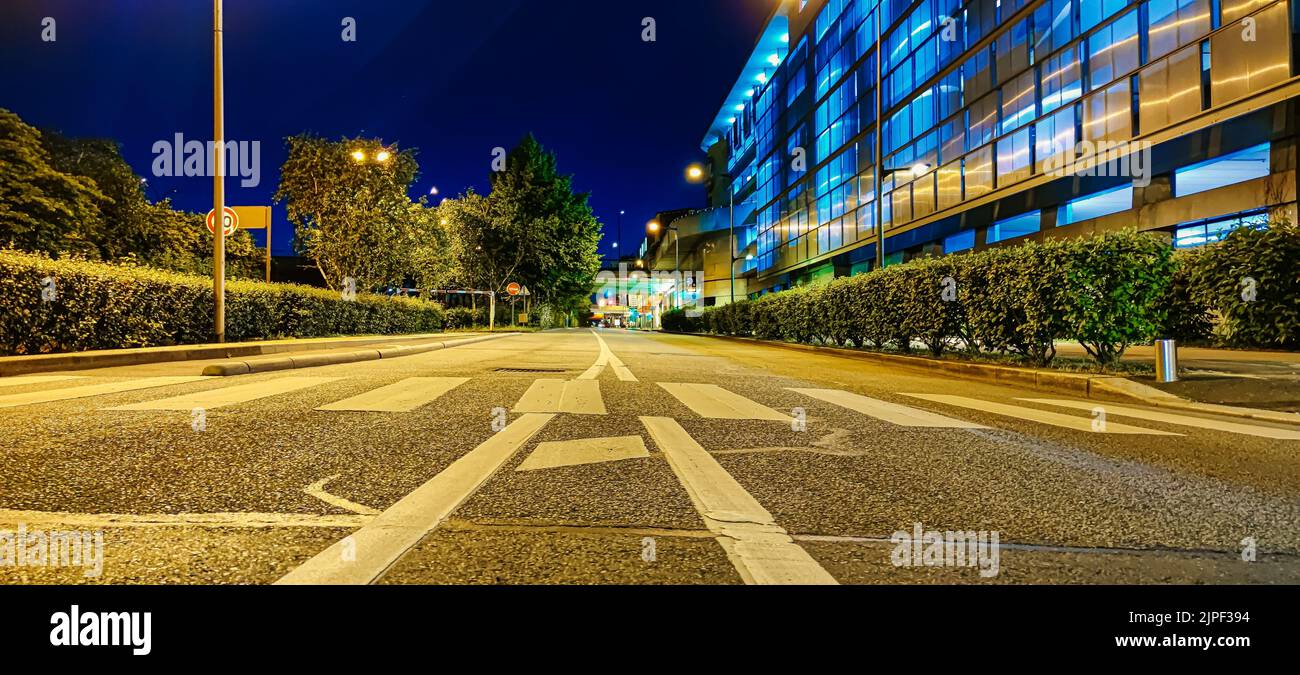 A night view of an empty road with a modern building and plants Stock ...