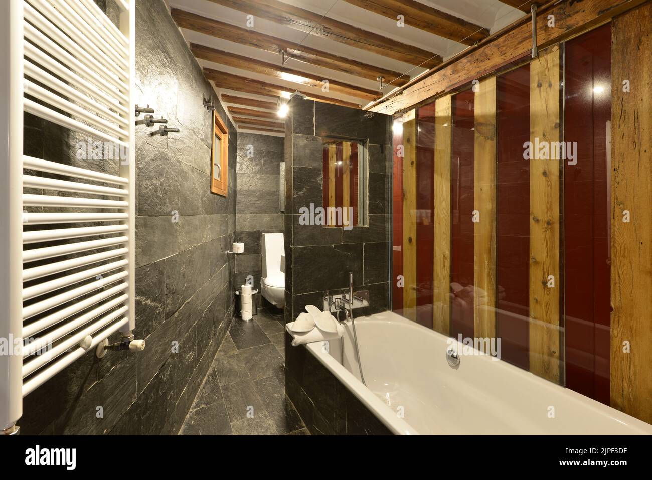 Spacious bathroom with slate tiles on walls and floors, built-in white ...