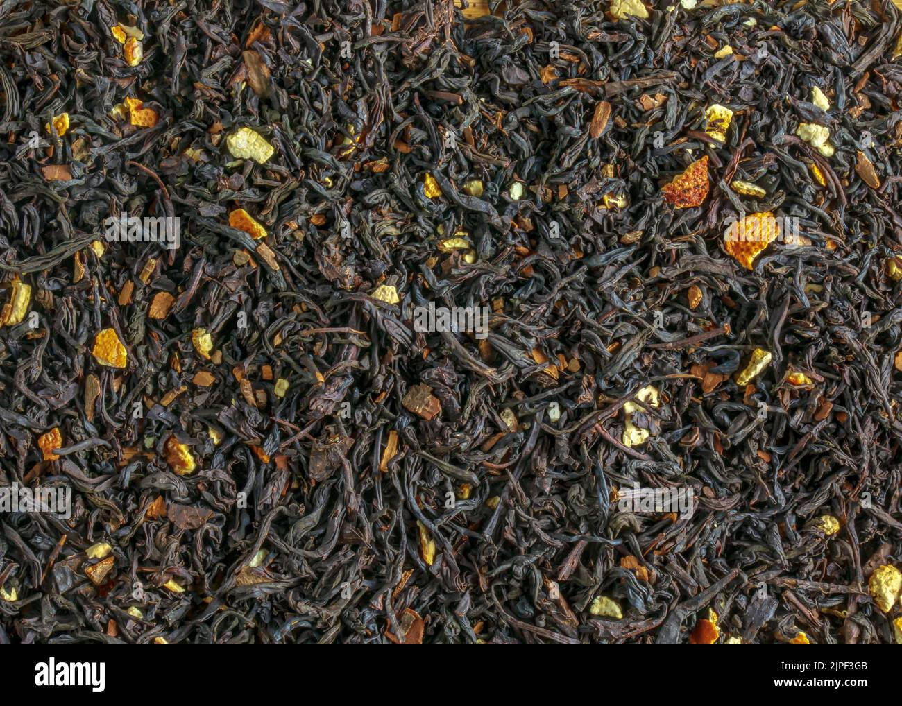 A Ceylon black tea. Background of leaf tea with pieces of citrus orange ...