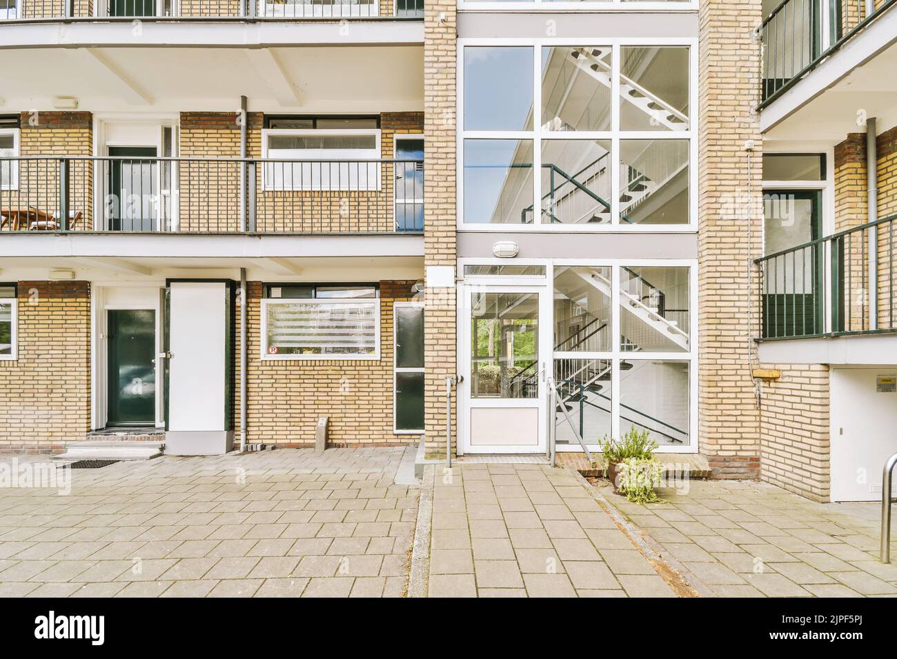 The front view of a brick building with signs,pavement and wooden doors ...