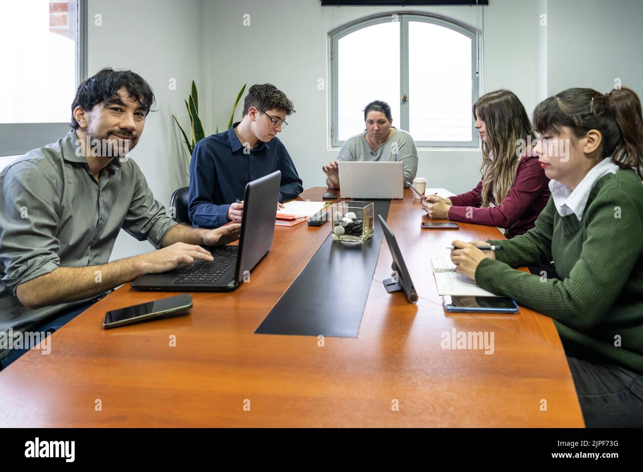 Group of employees sitting around the office meeting table working on ...