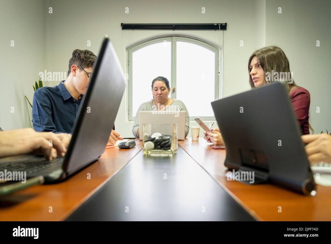 Group of employees sitting around the office meeting table working on ...