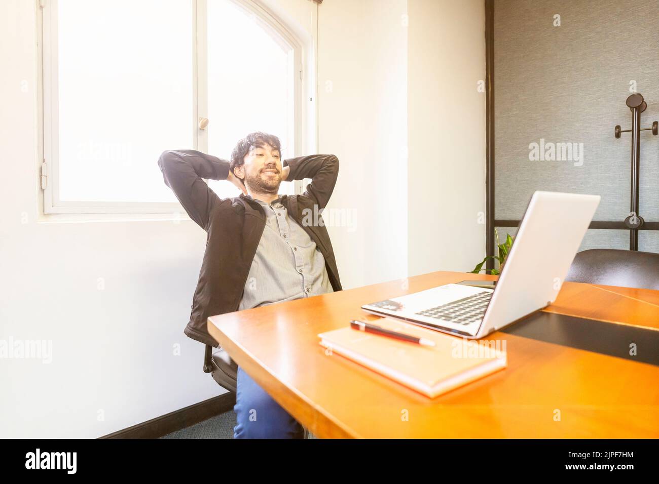 Businessman sitting at the head of the meeting table with his hands ...