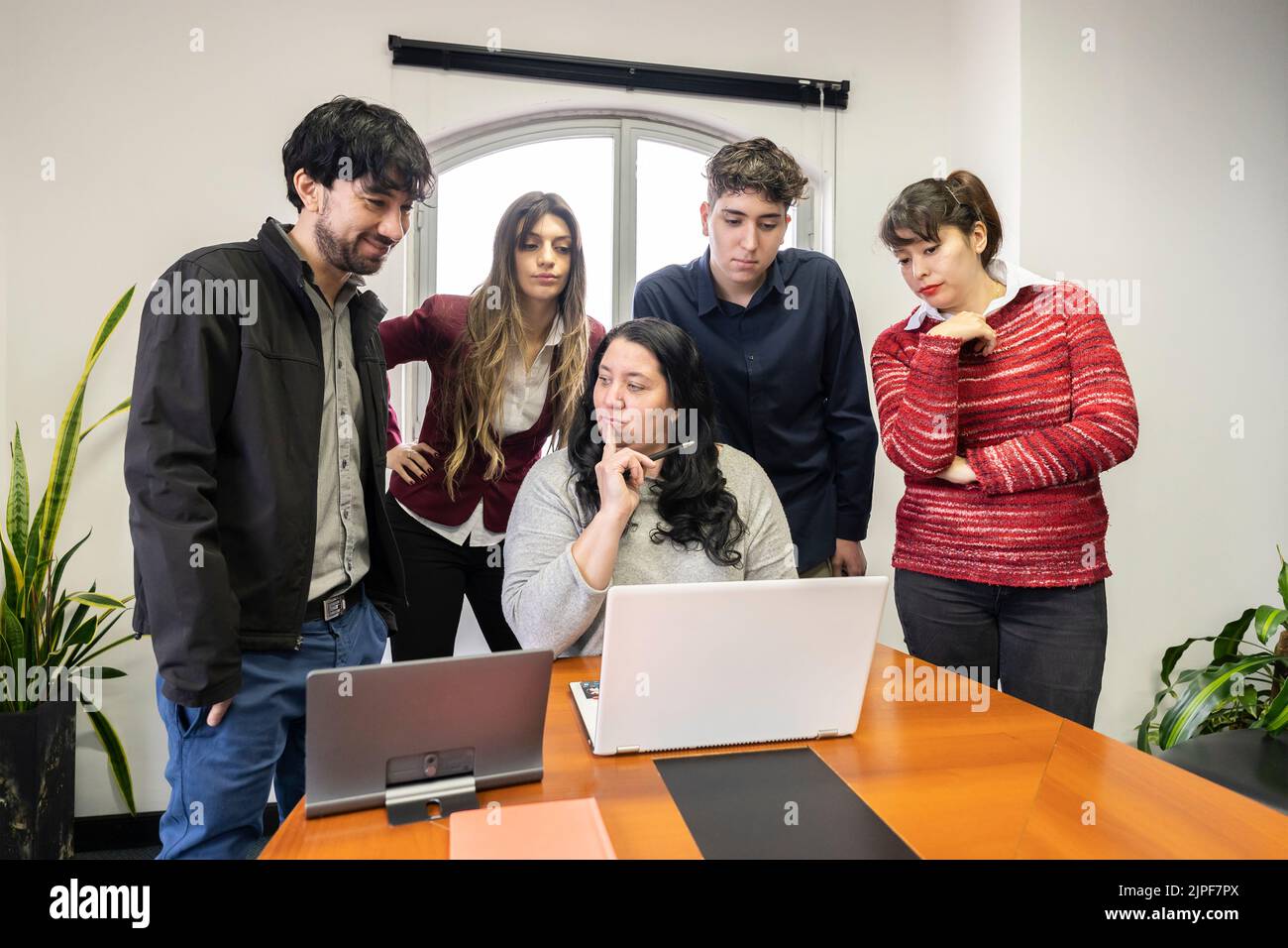 Group of employees standing around their boss at the meeting table ...