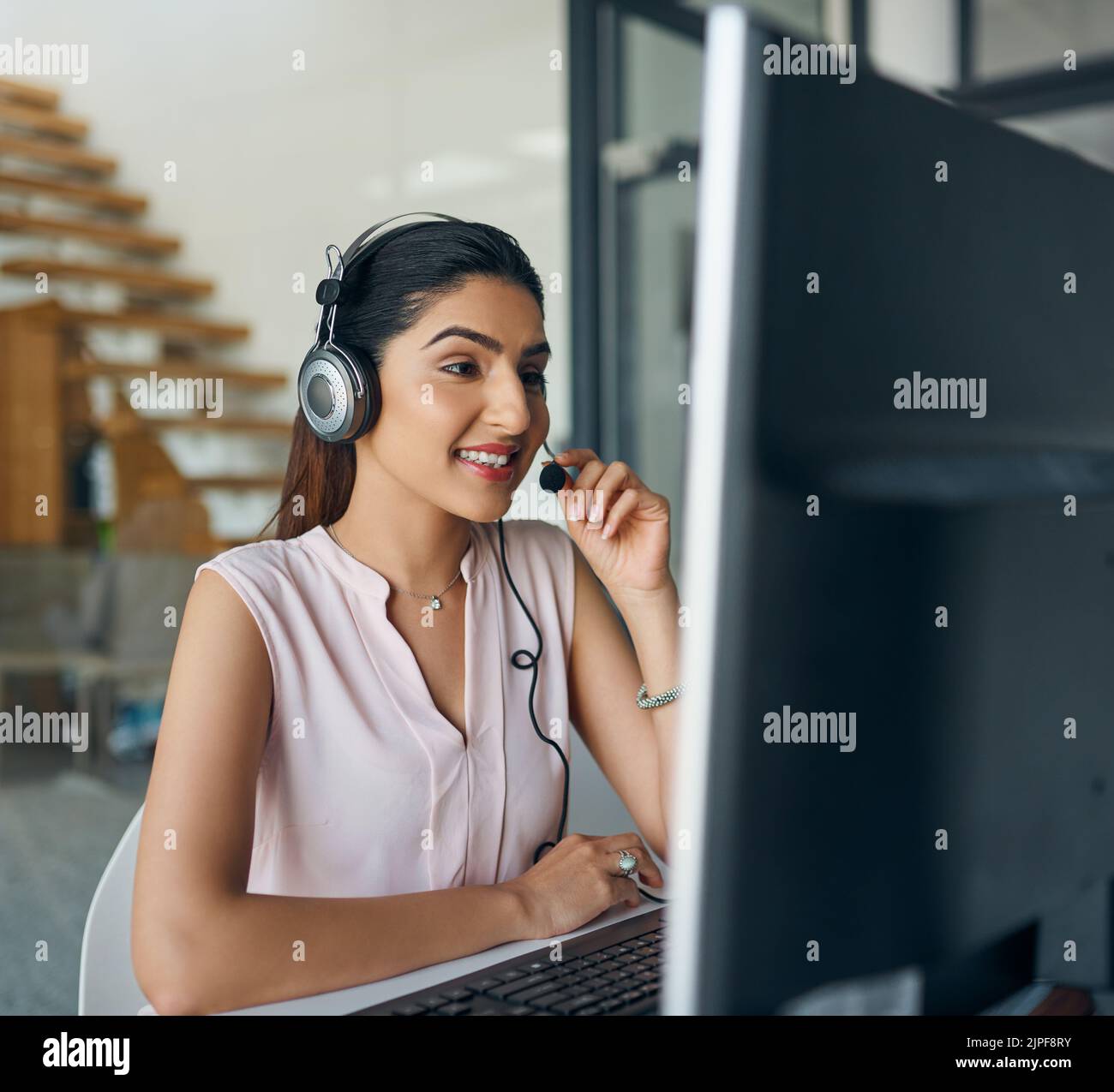 At the ready to handle any call. a young woman working on a computer in ...