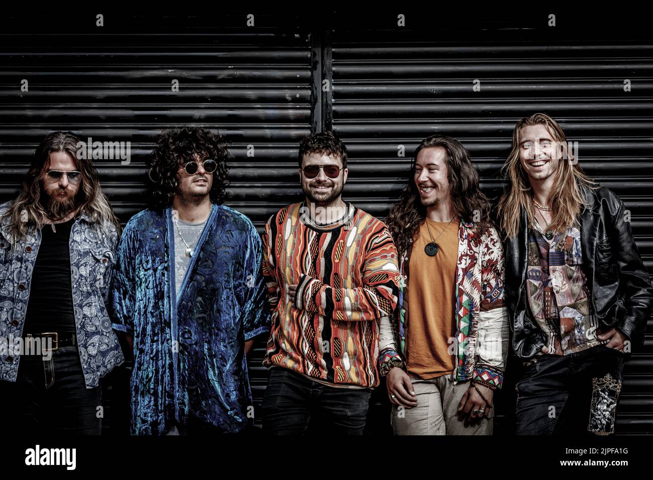 Five stylish young men in colorful, eclectic clothing stand side by ...