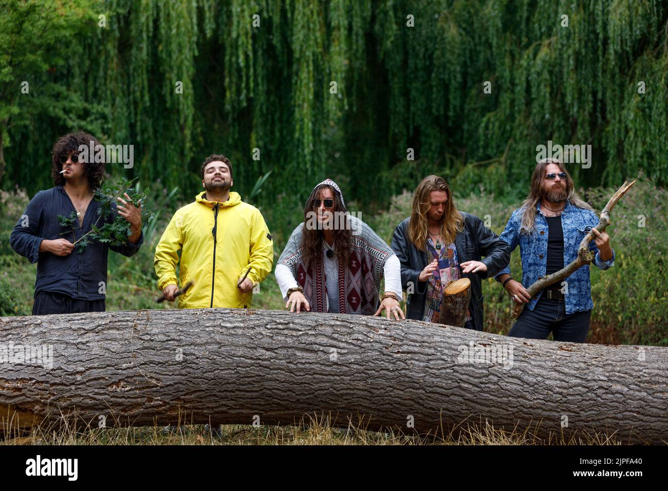 Five men from a rock group, play pretend instruments in a woodland ...
