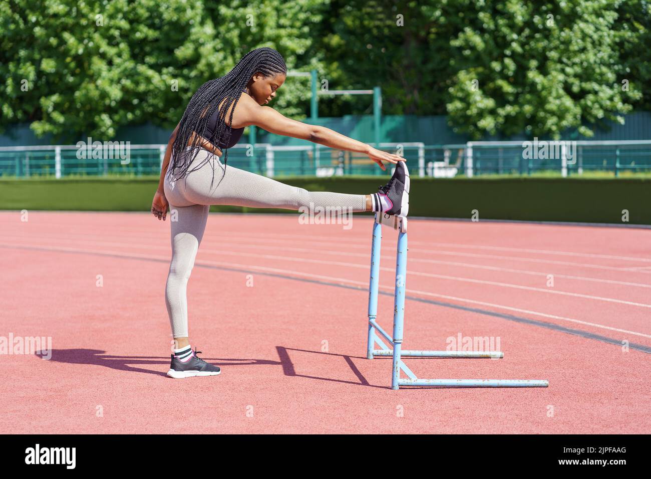 Young African American female puts leg on hurdles barrier to do ...