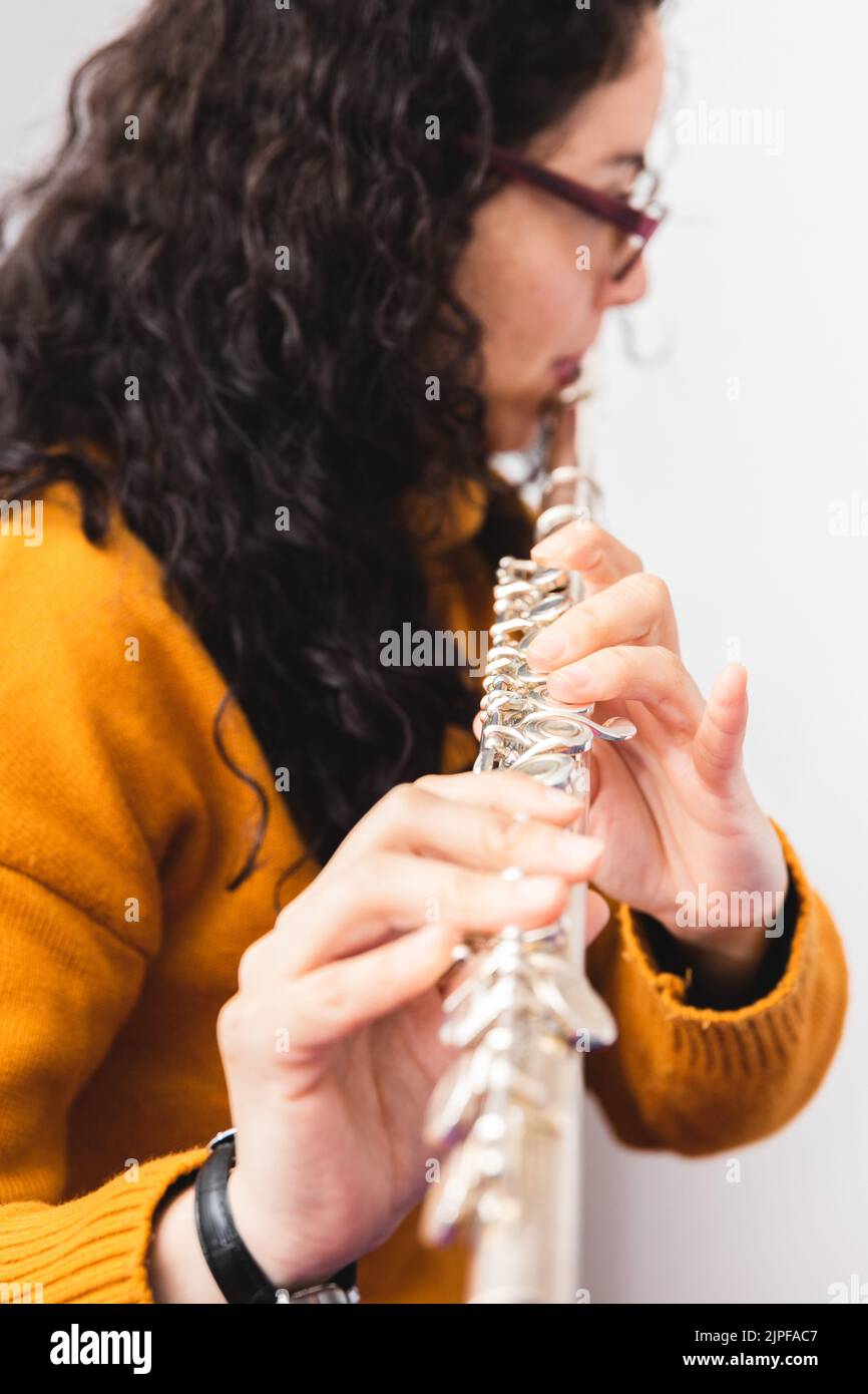 Brunette woman wearing a yellow sweater, and playing a transverse flute ...