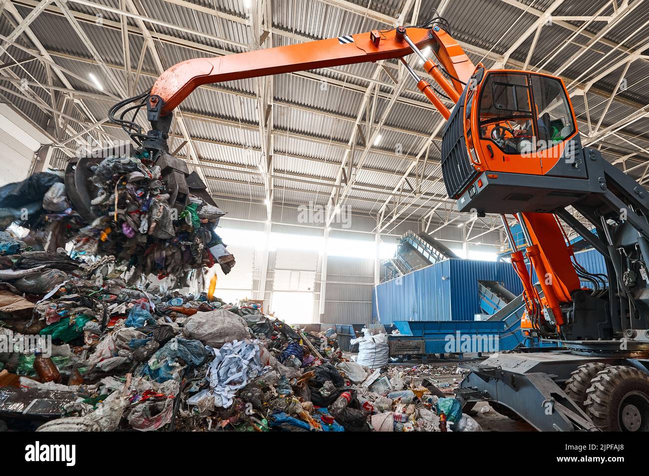 Excavator grabs trash in warehouse of waste processing plant Stock ...