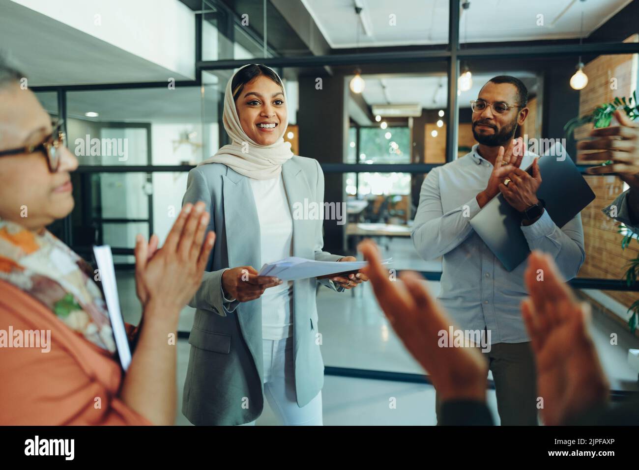 Multicultural businesspeople applauding their colleague during a ...