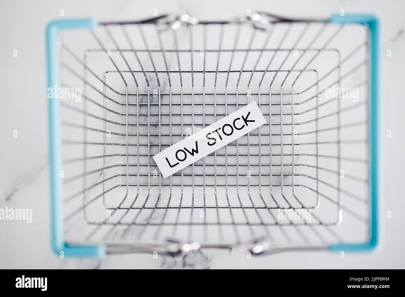 Low stock text in front of empty shopping basket on white background ...