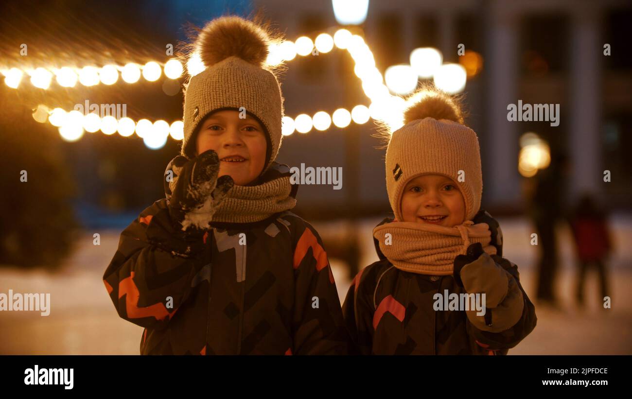 Two little kids standing on public ice rink and looking in the camera ...