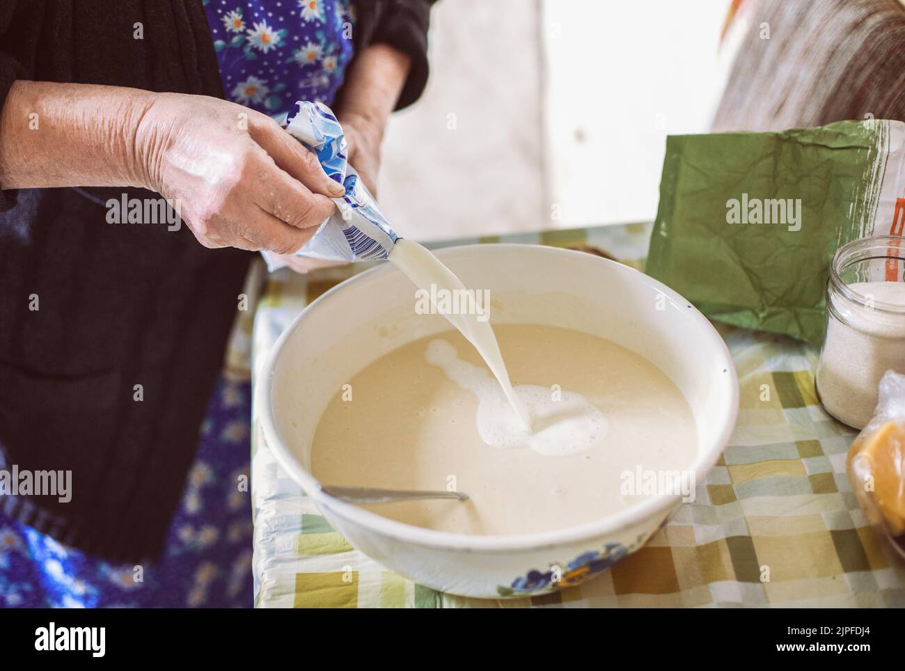 Grandmother pouring milk into pancake batter Stock Photo - Alamy