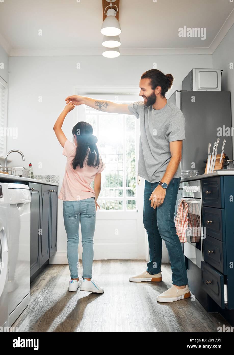 Father and daughter dancing together, having family fun in the kitchen ...