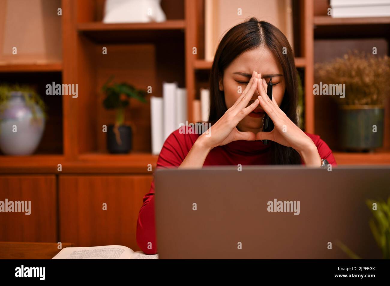 Stressed and upset young Asian businesswoman working on her project on ...
