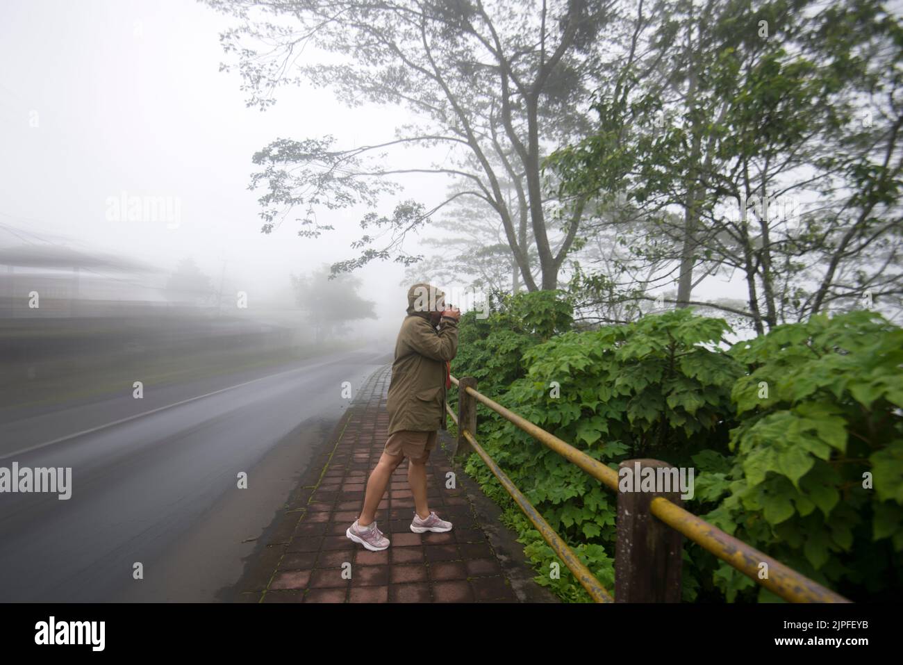 Woman photographer standing on sidewalk alone with camera taking ...