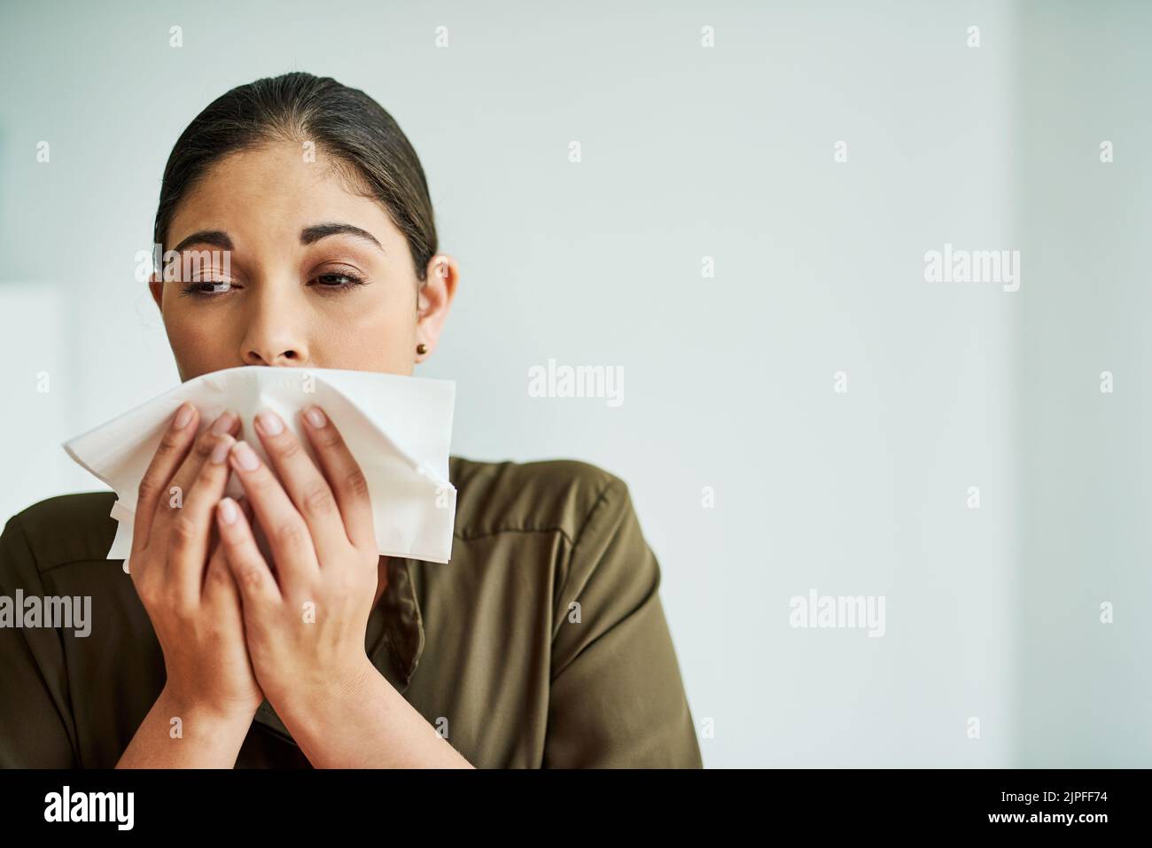 The sneezes just keep on coming. a young businesswoman blowing her nose ...