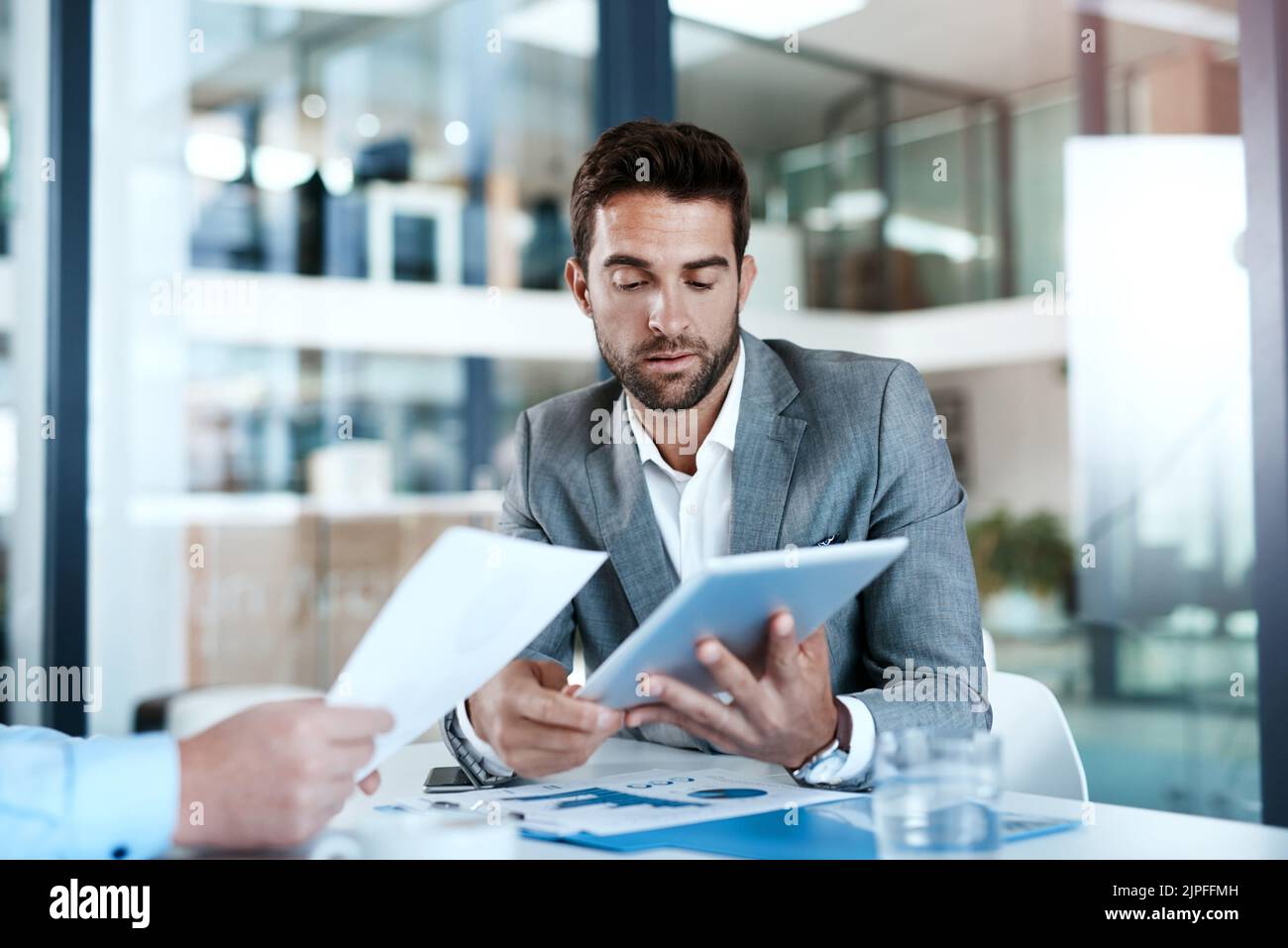 Getting down to the data. two businessmen using a digital tablet while ...