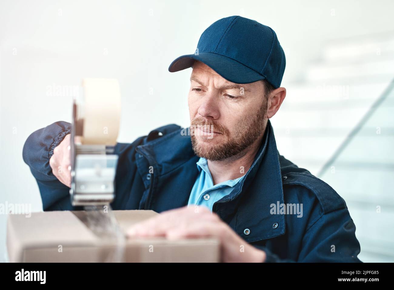 Sealing up the package before the long journey. a handsome delivery man ...