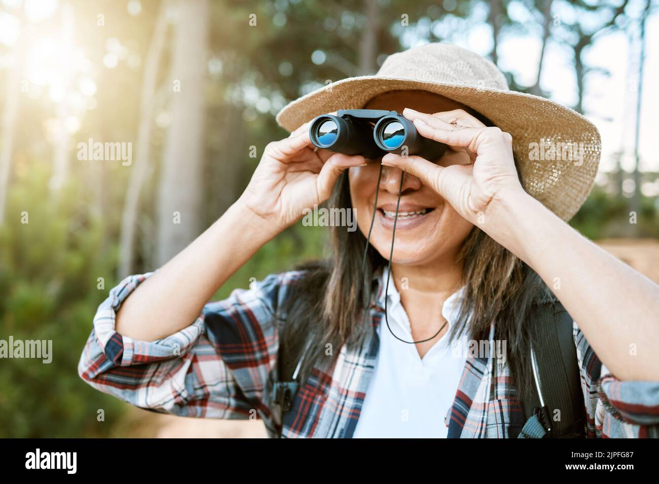 Female tourist hiking, looking through binoculars at wild birds in the ...