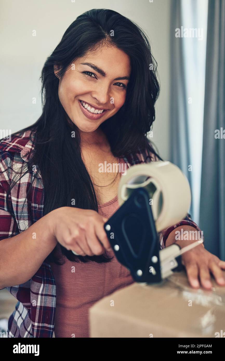 Packed and ready to make this move. Portrait of a young woman using ...