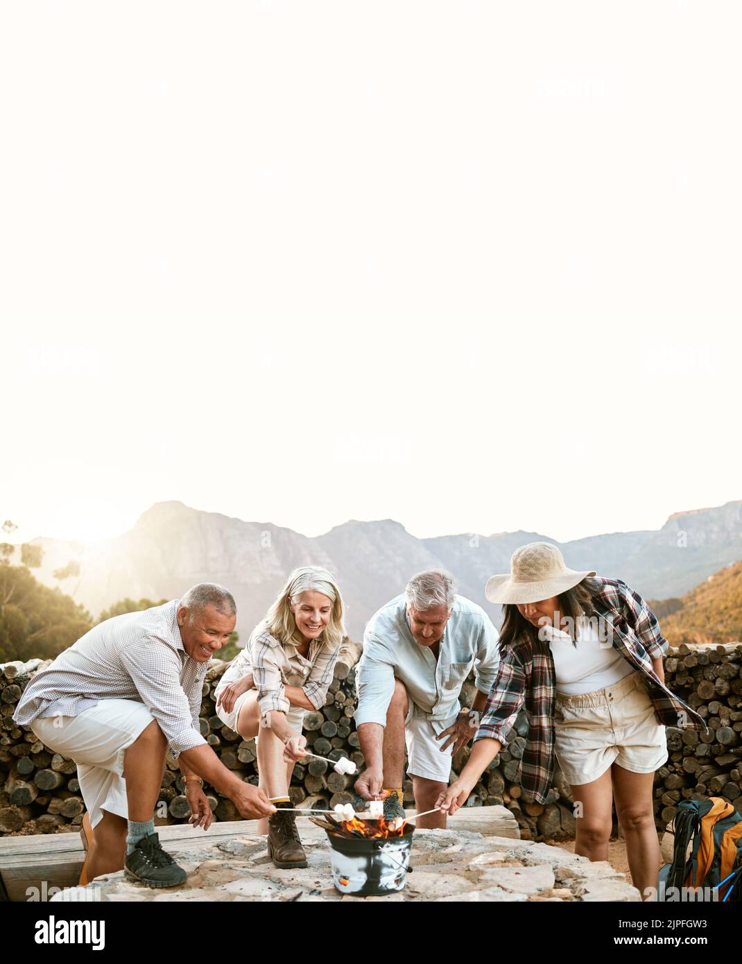 Melting marshmallows by a fire on a nature getaway vacation, senior ...