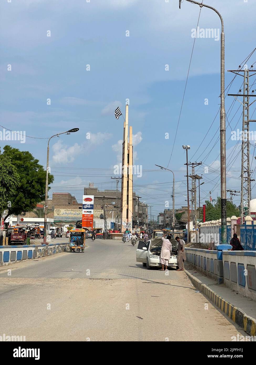 A vertical shot of people and cars on a street from Kandiaro, Pakistan ...
