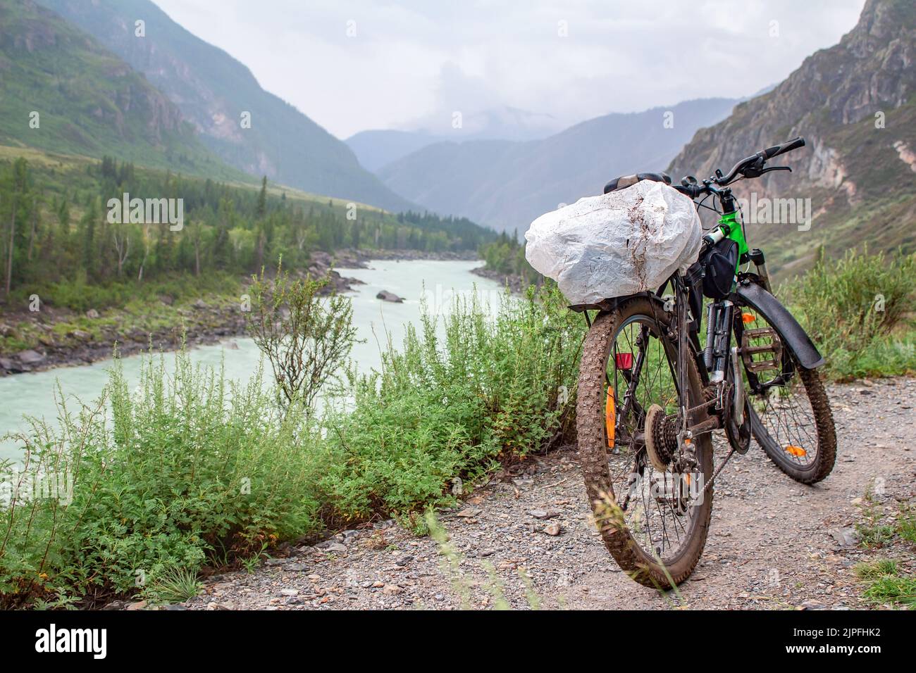 view of a dirty sports mountain bike standing on a stone footpath, a ...