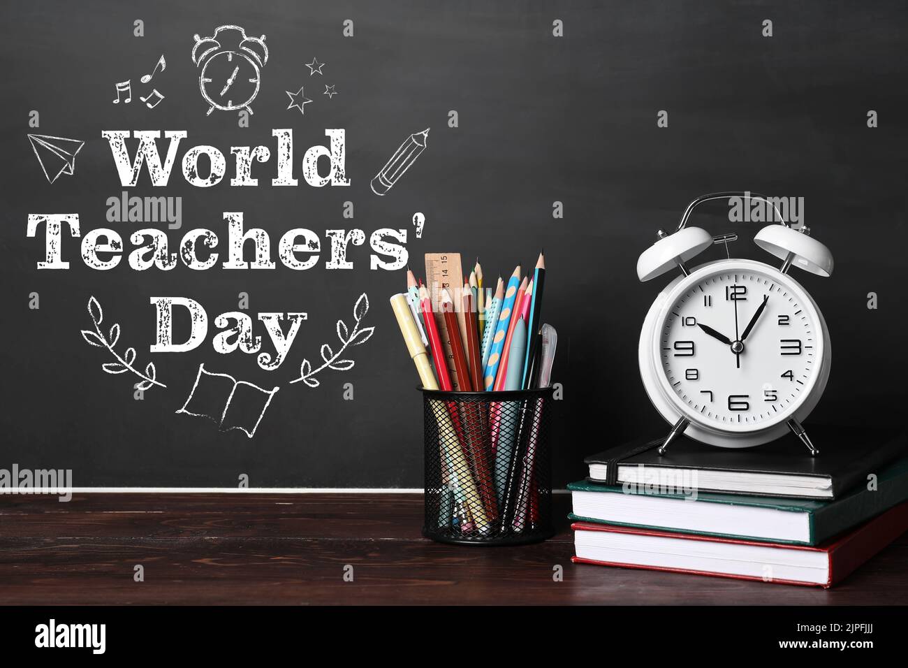 School stationery, books and alarm clock on table in classroom. World ...