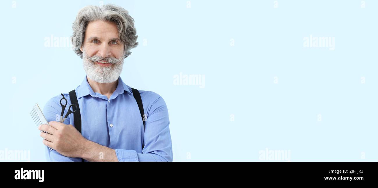 Handsome mature hairdresser on light blue background with space for ...