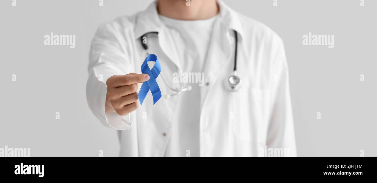 Doctor holding blue ribbon on light background, closeup. Prostate ...