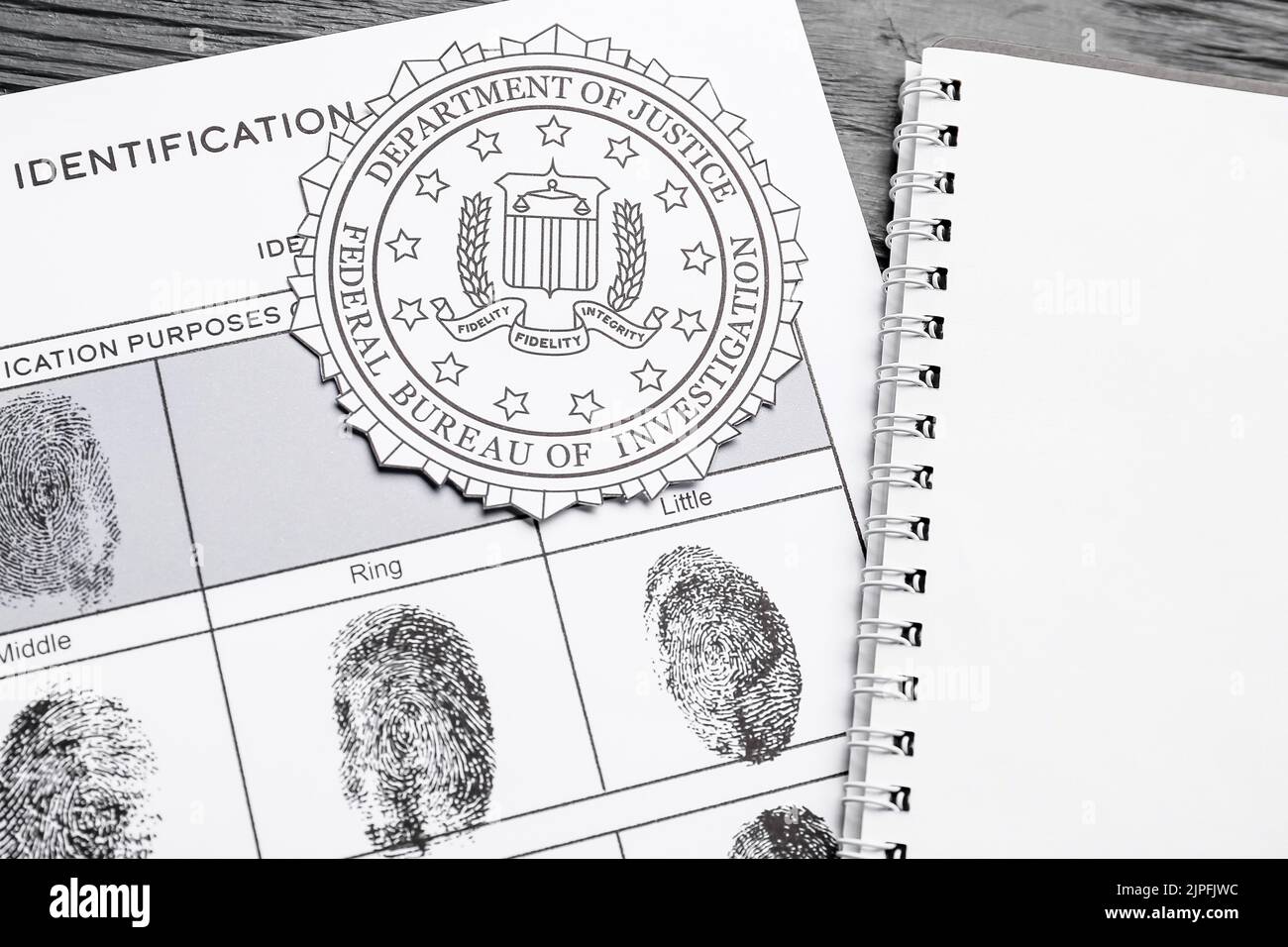 Paper sheet with finger prints, seal of FBI and notebook on dark wooden ...