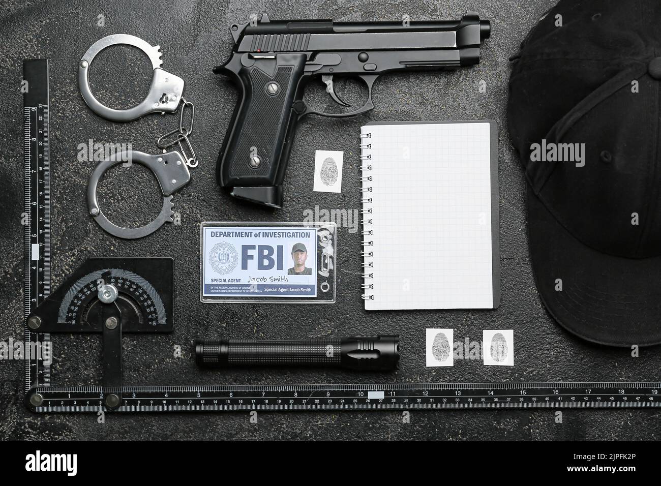 Notebook with document of FBI agent and accessories on dark background ...