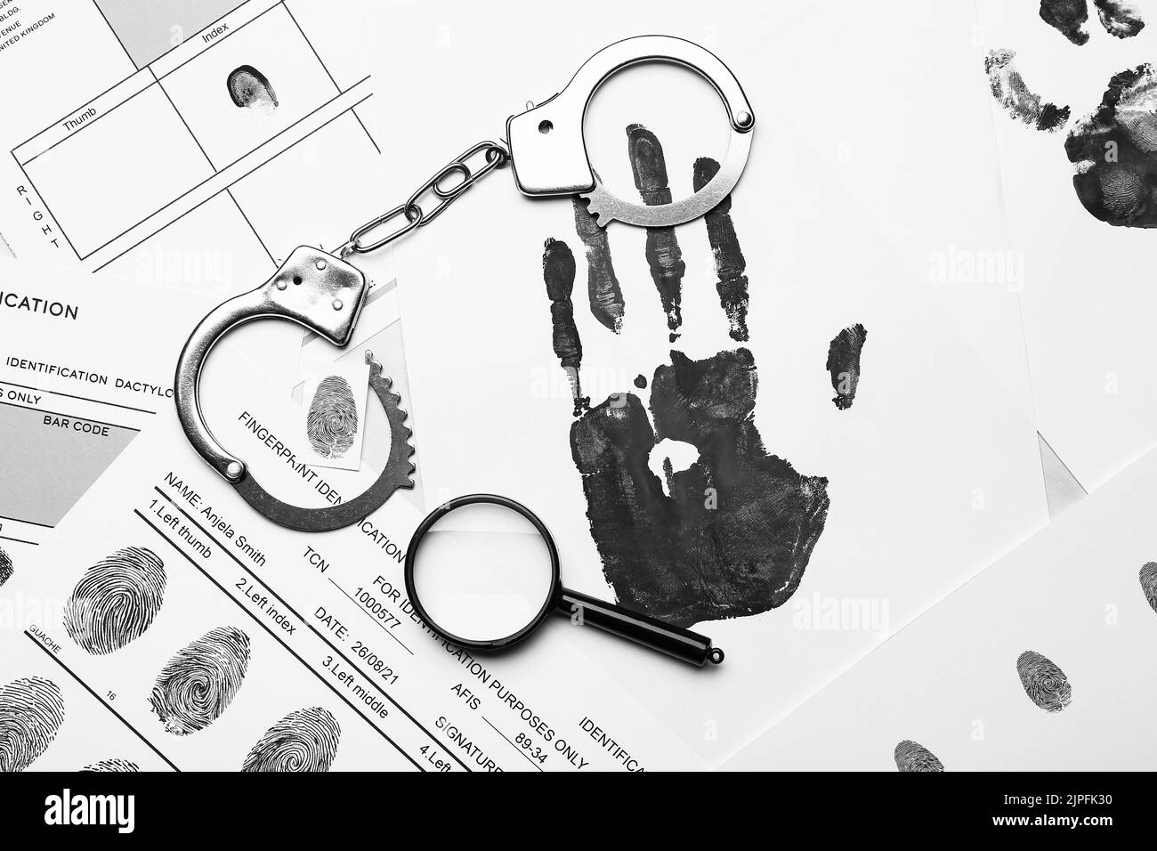 Paper sheets with palm and finger prints, handcuffs and magnifier, top ...