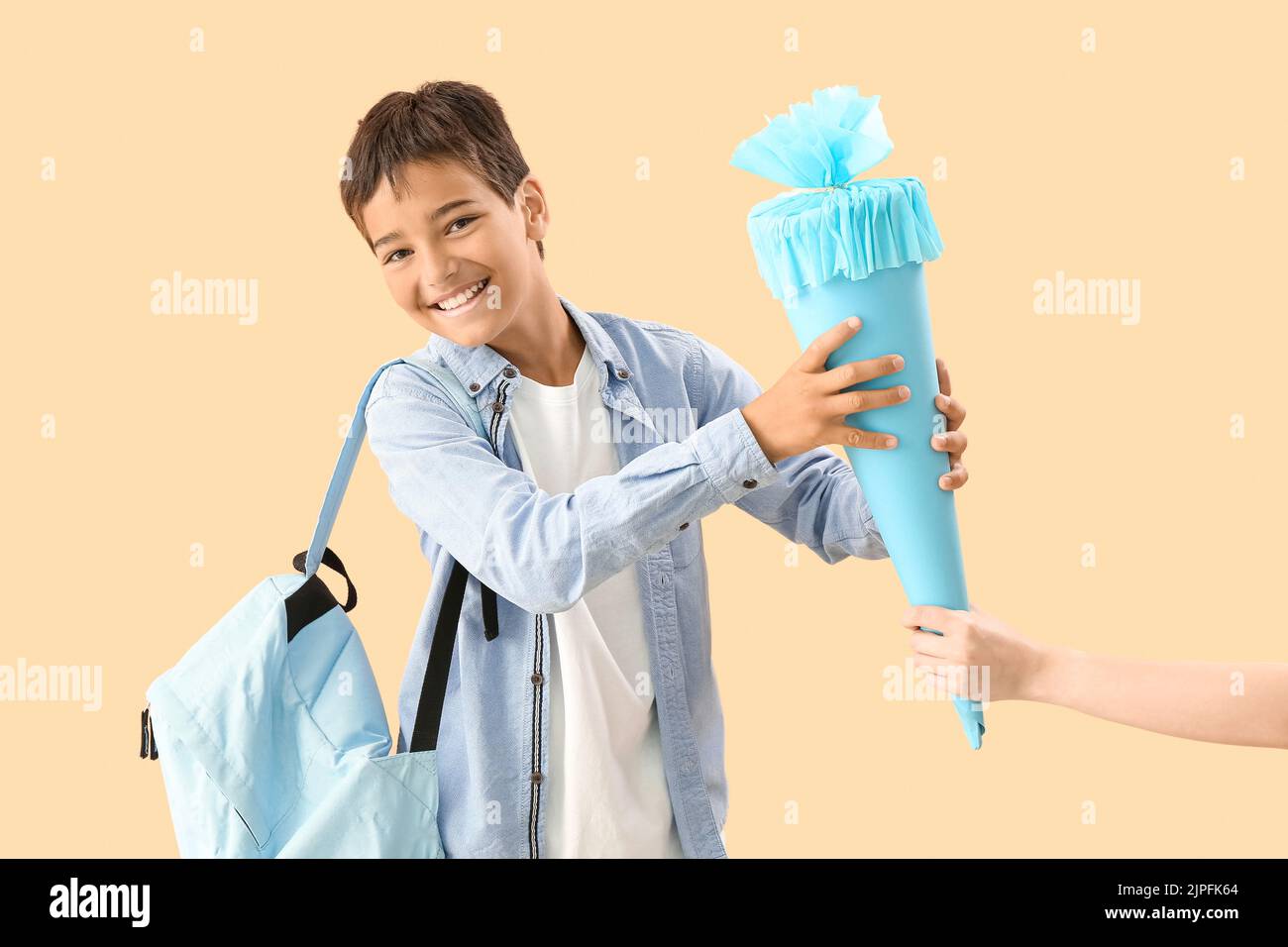 Little boy receiving blue school cone on beige background Stock Photo ...