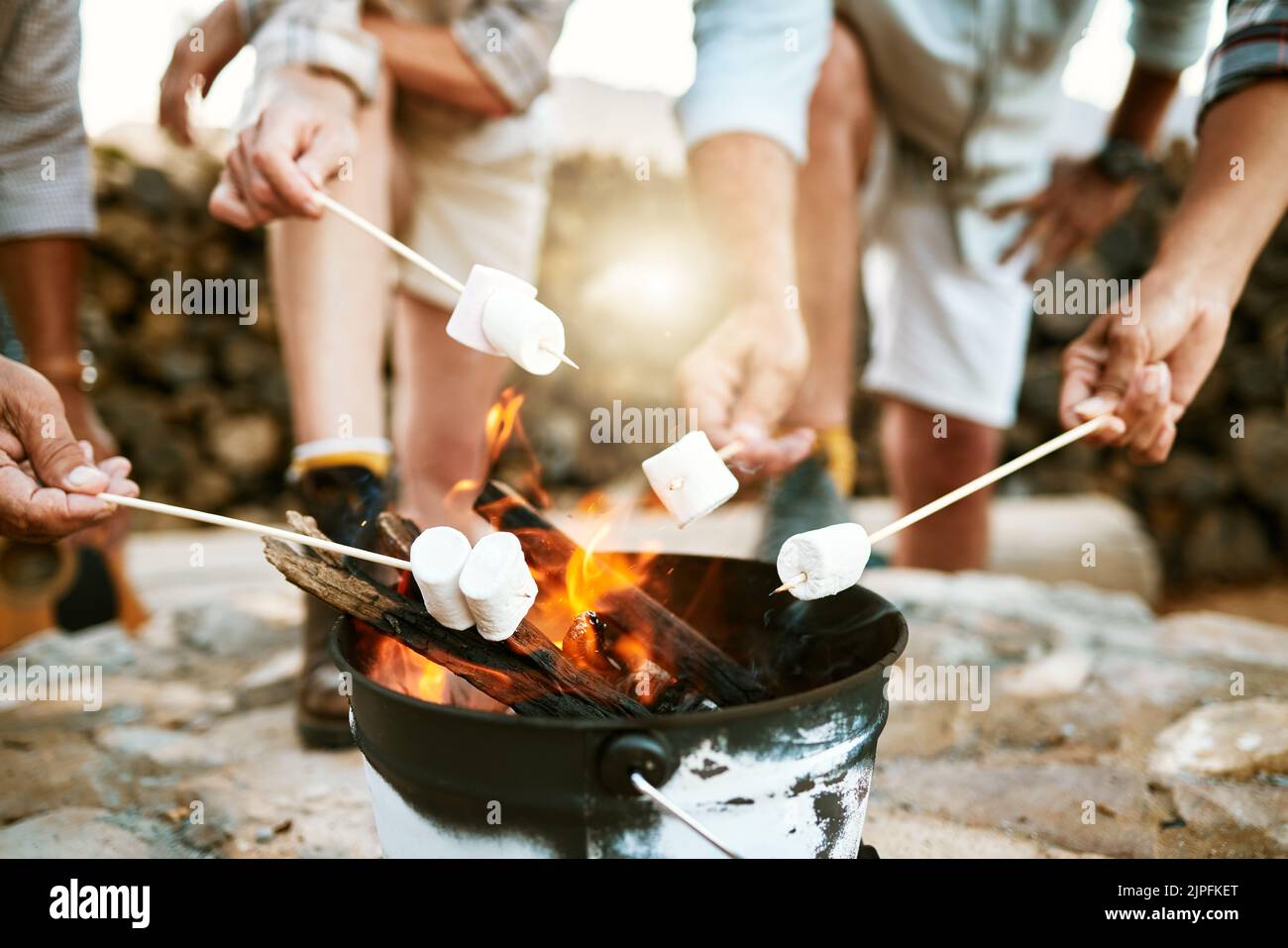 Melting marshmallows by a fire on a nature getaway vacation, group ...