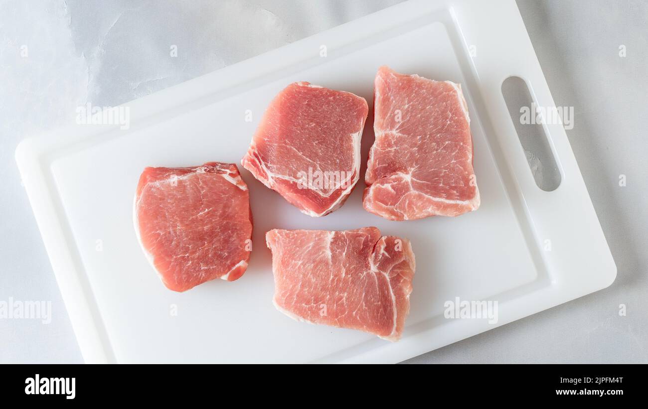 Raw pork chops close up on cutting board, flat lay, marble background ...