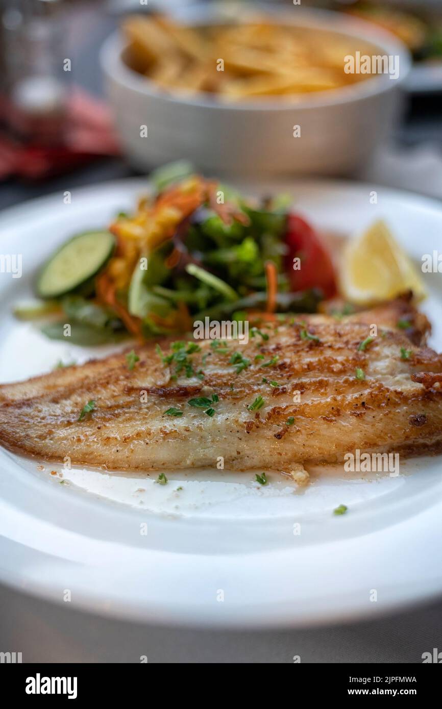 Pan fried Plaice fillet with fresh salad and a bowl of fries Stock ...