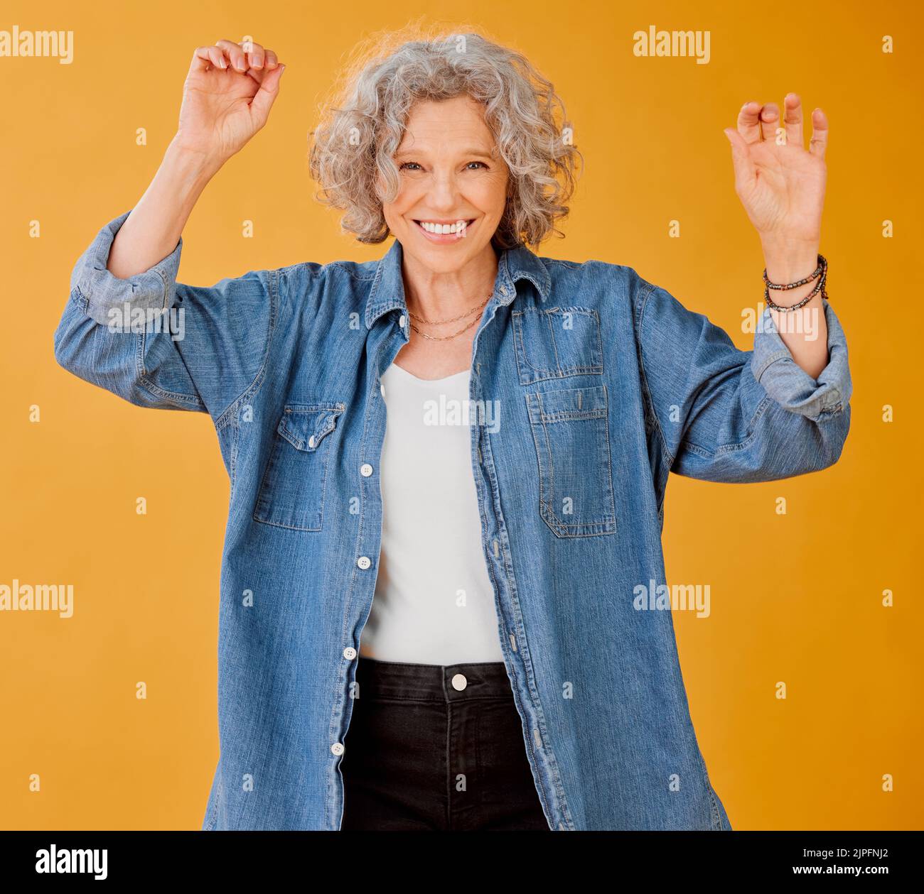 Trendy, funky and fun mature female celebrate freedom against orange ...