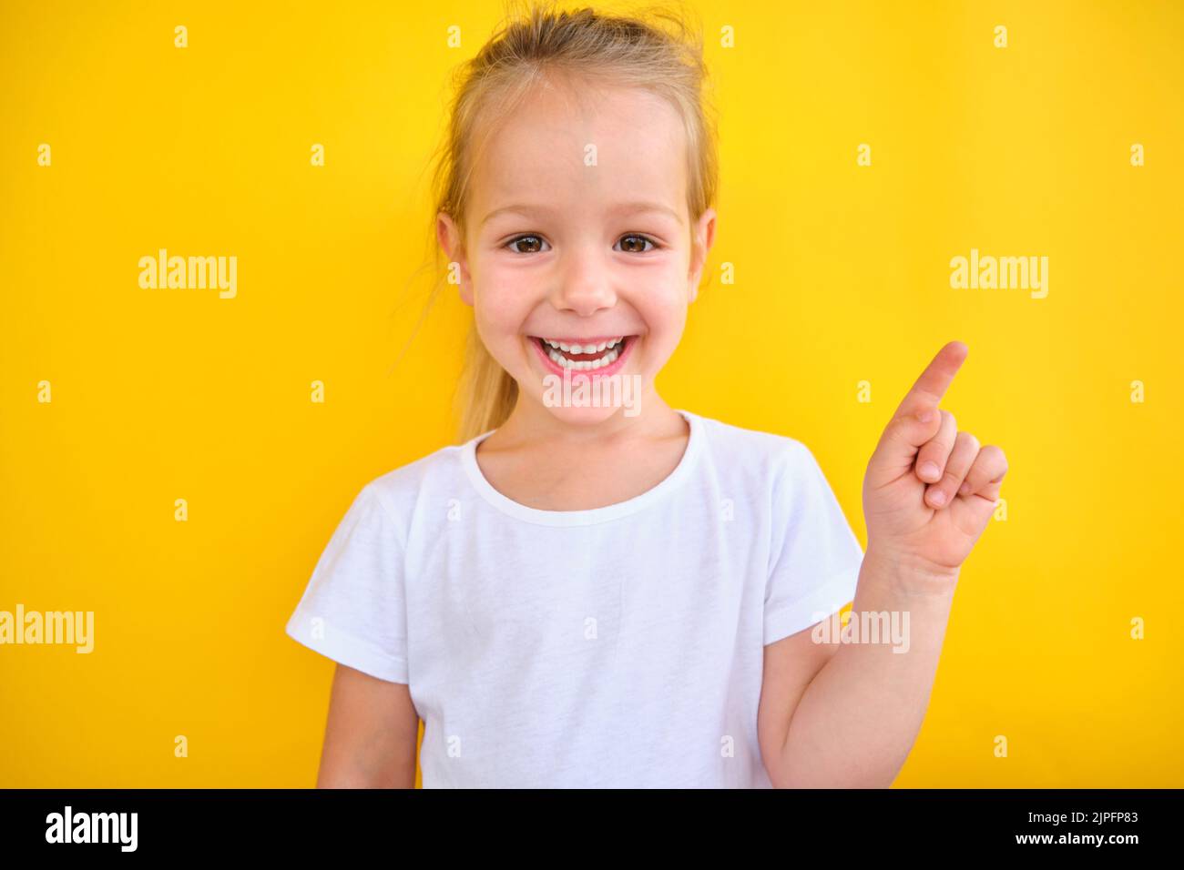 Portrait preschool girl showing pointing up copy space advertising sale ...