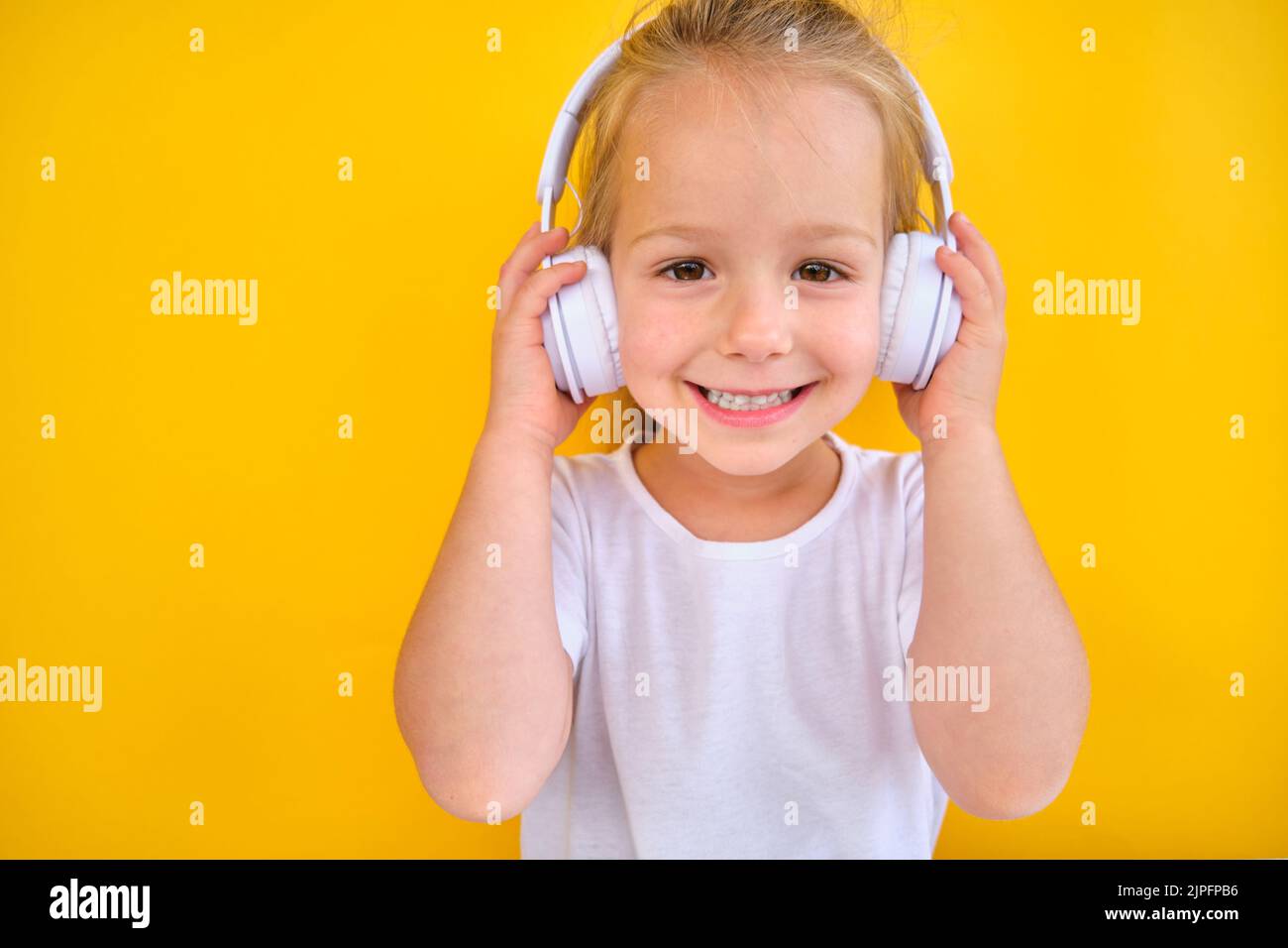 portrait smiling preschool girl listen music wireless white headphones ...