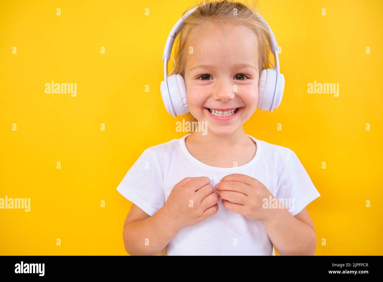 amazed smiling preschool little girl listening music white headphones ...