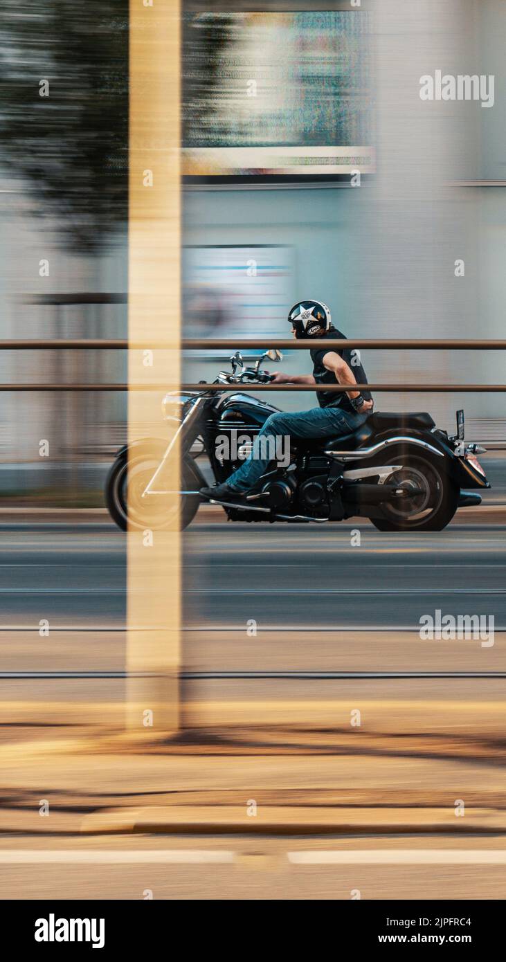 A vertical shot of a man in a helmet riding a motorbike in Milan Stock ...
