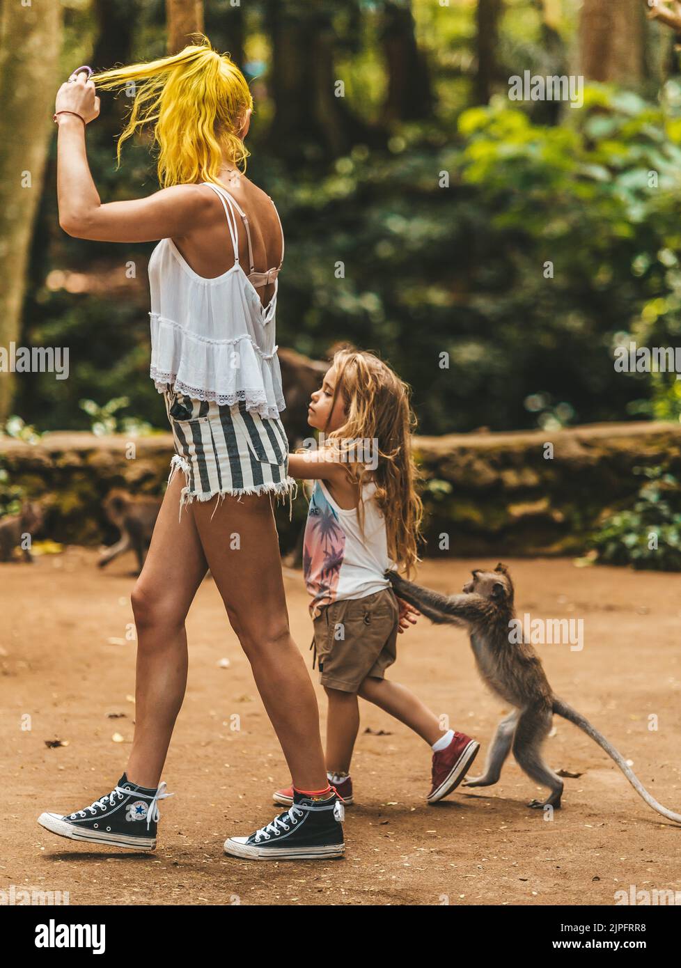 Little monkey grabs small boy for the clothes. The boy holds his mom's ...