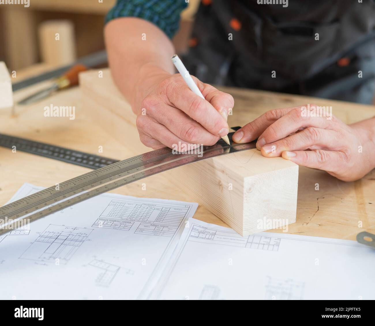 A carpenter measures wooden planks and makes marks with a pencil in a ...