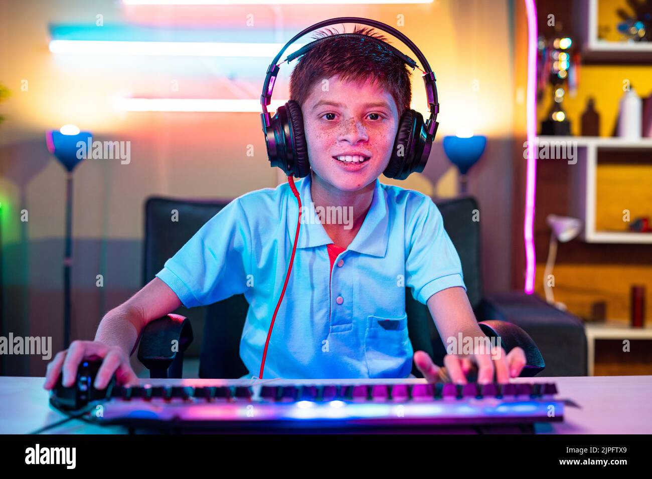 Happy teenager kid with headphones playing live video game by looking ...